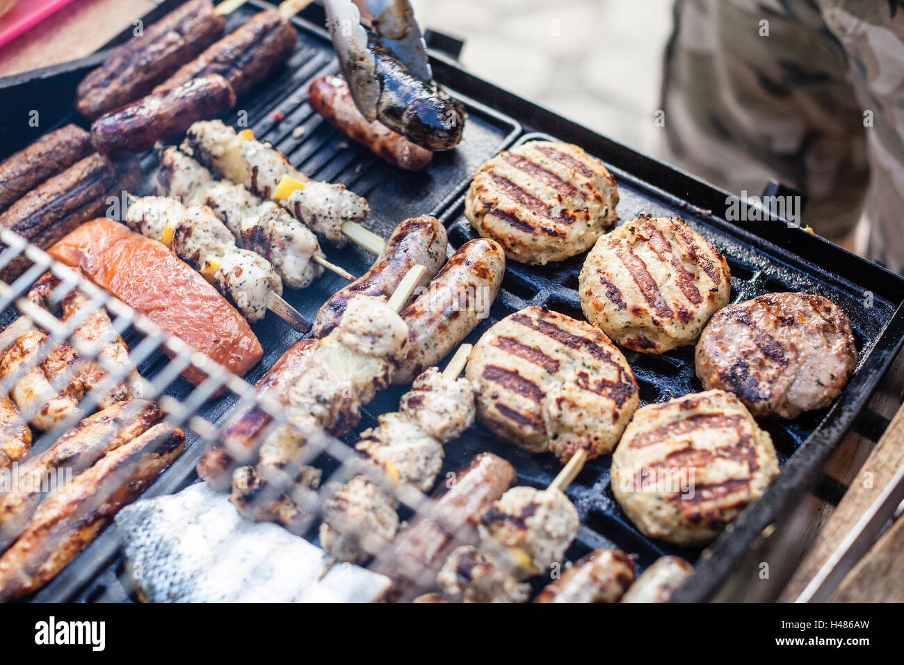 Smokey gas barbeque cooking various meats (burgers, sausages, fish ...