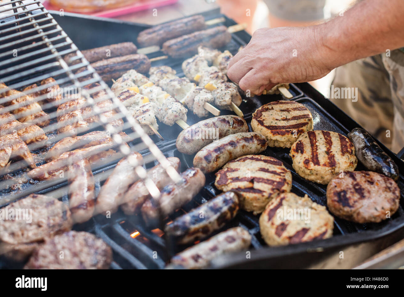Smokey gas barbeque cooking various meats (burgers, sausages, fish ...