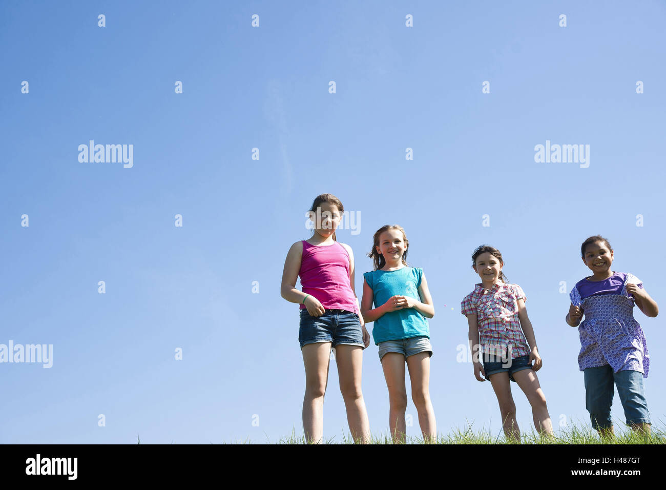 four girls stand on a meadow Stock Photo - Alamy
