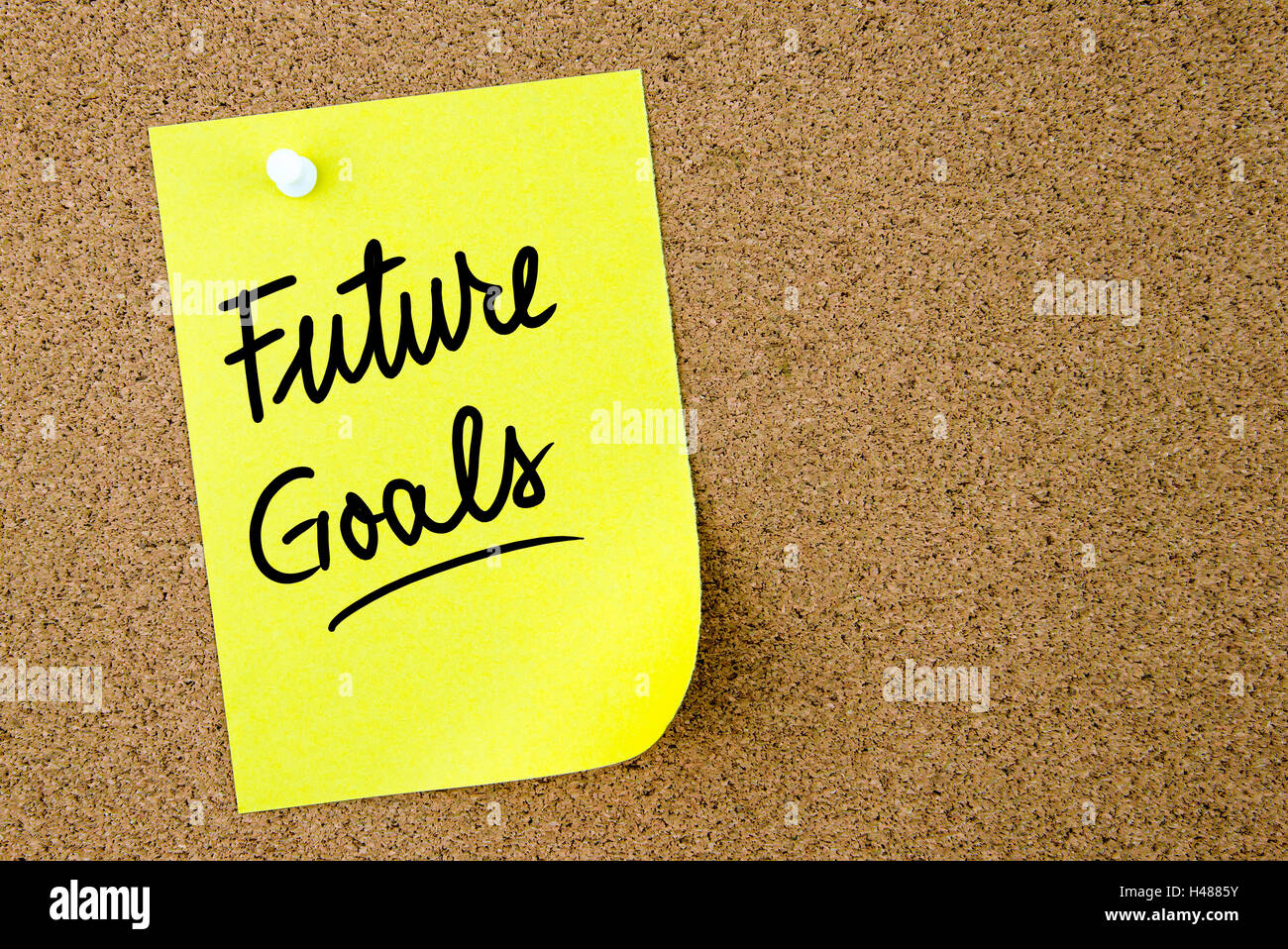Future Goals text written on yellow paper note pinned on cork board ...