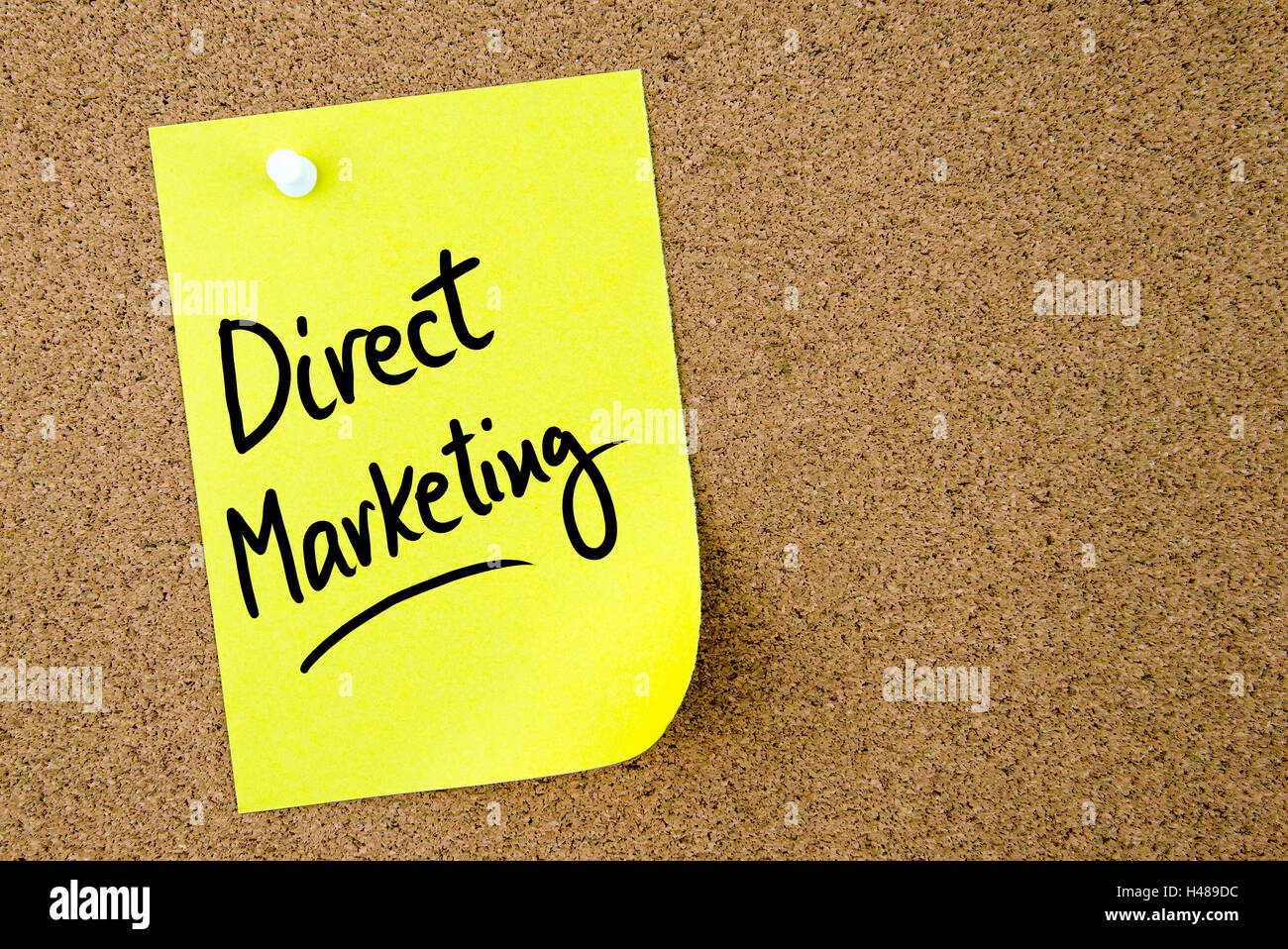Direct Marketing text written on yellow paper note pinned on cork board ...