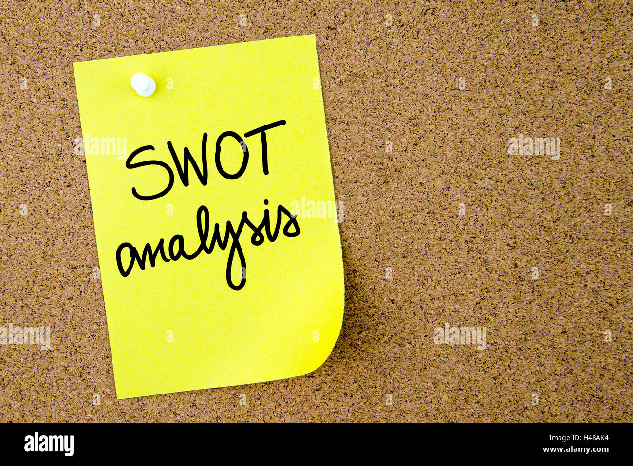 SWOT Analysis text written on yellow paper note pinned on cork board ...