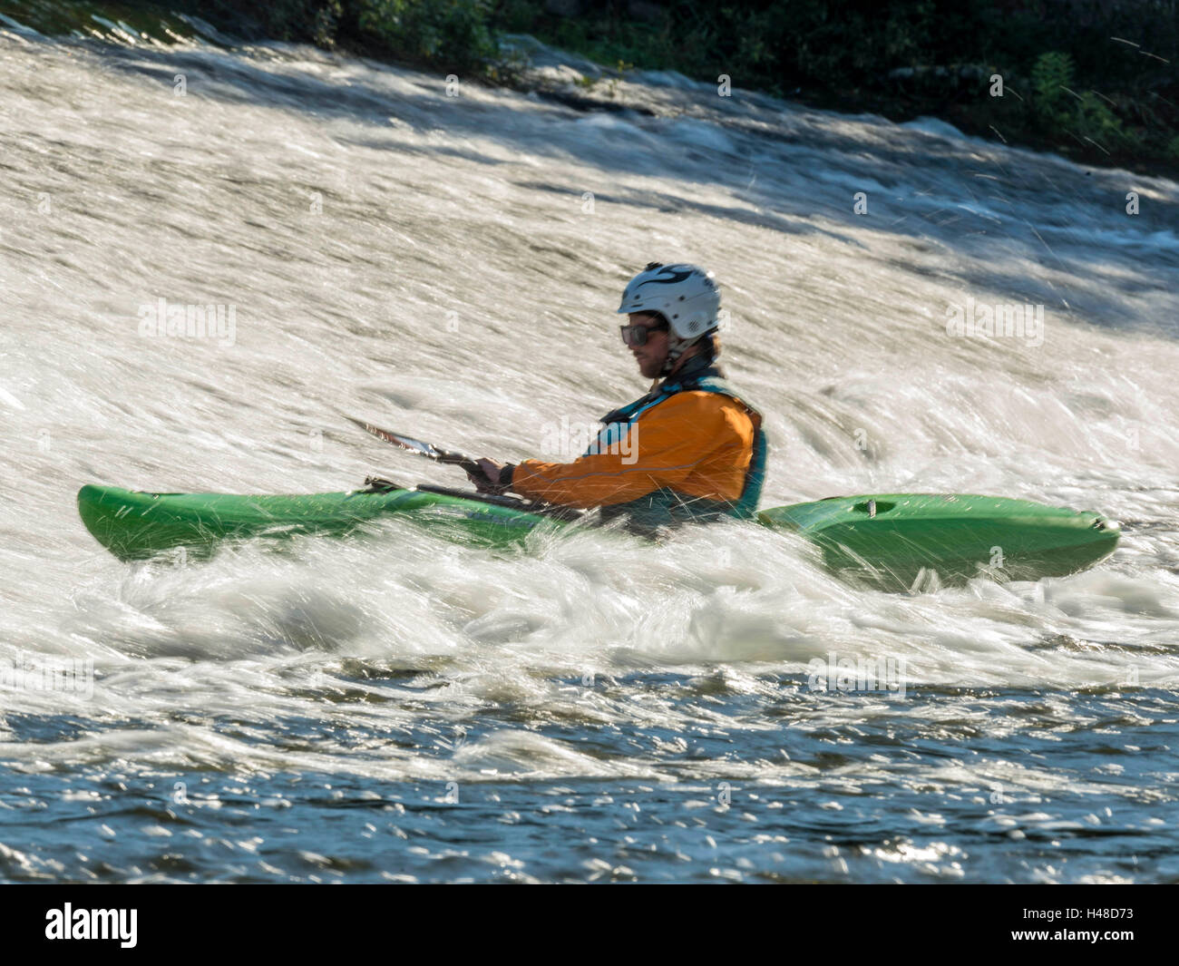 Male adult White Water Kayaking along a River Exe Weir on a bright ...