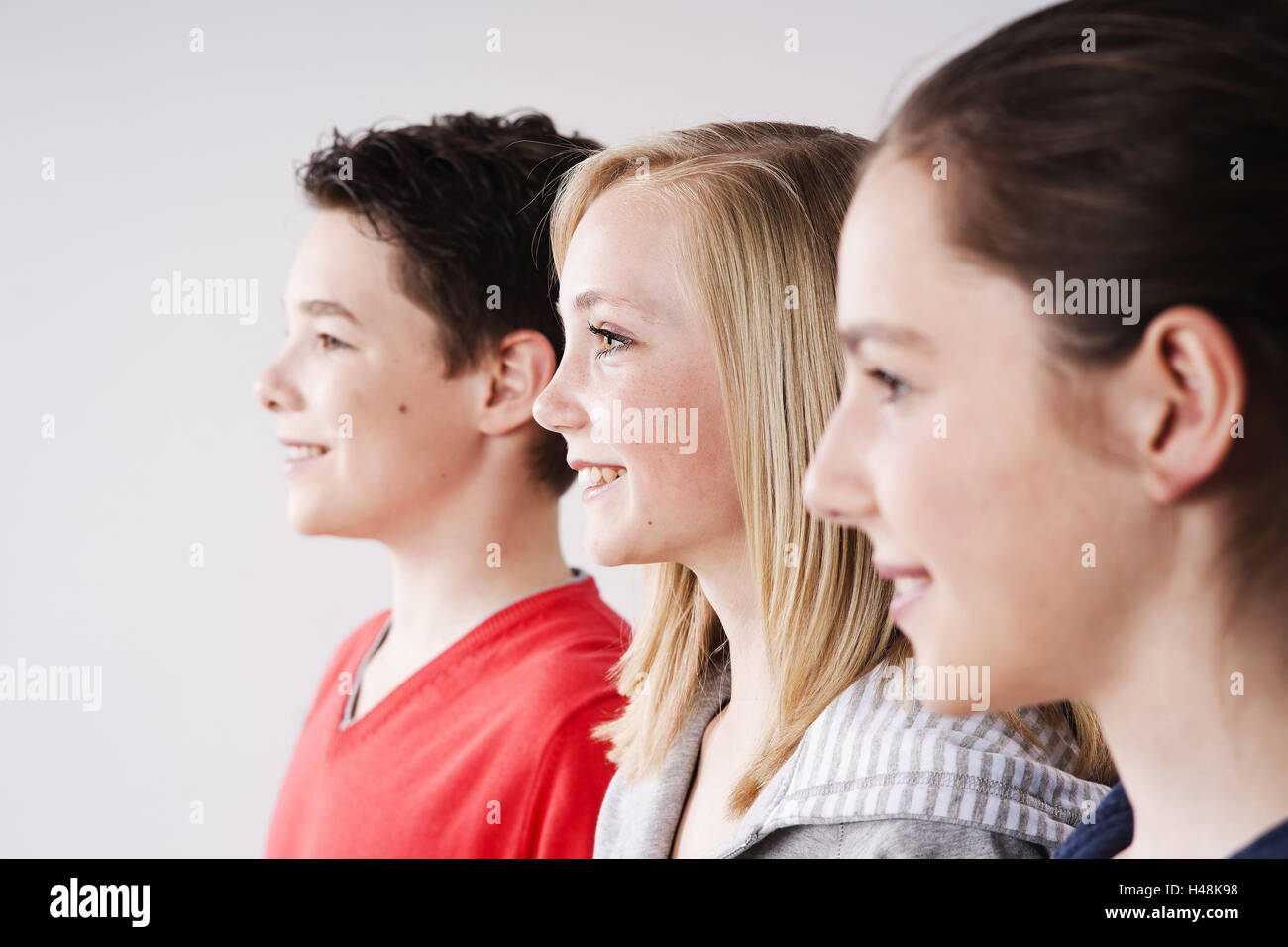 Teenage girls, boy, smile, side view, studio Stock Photo - Alamy