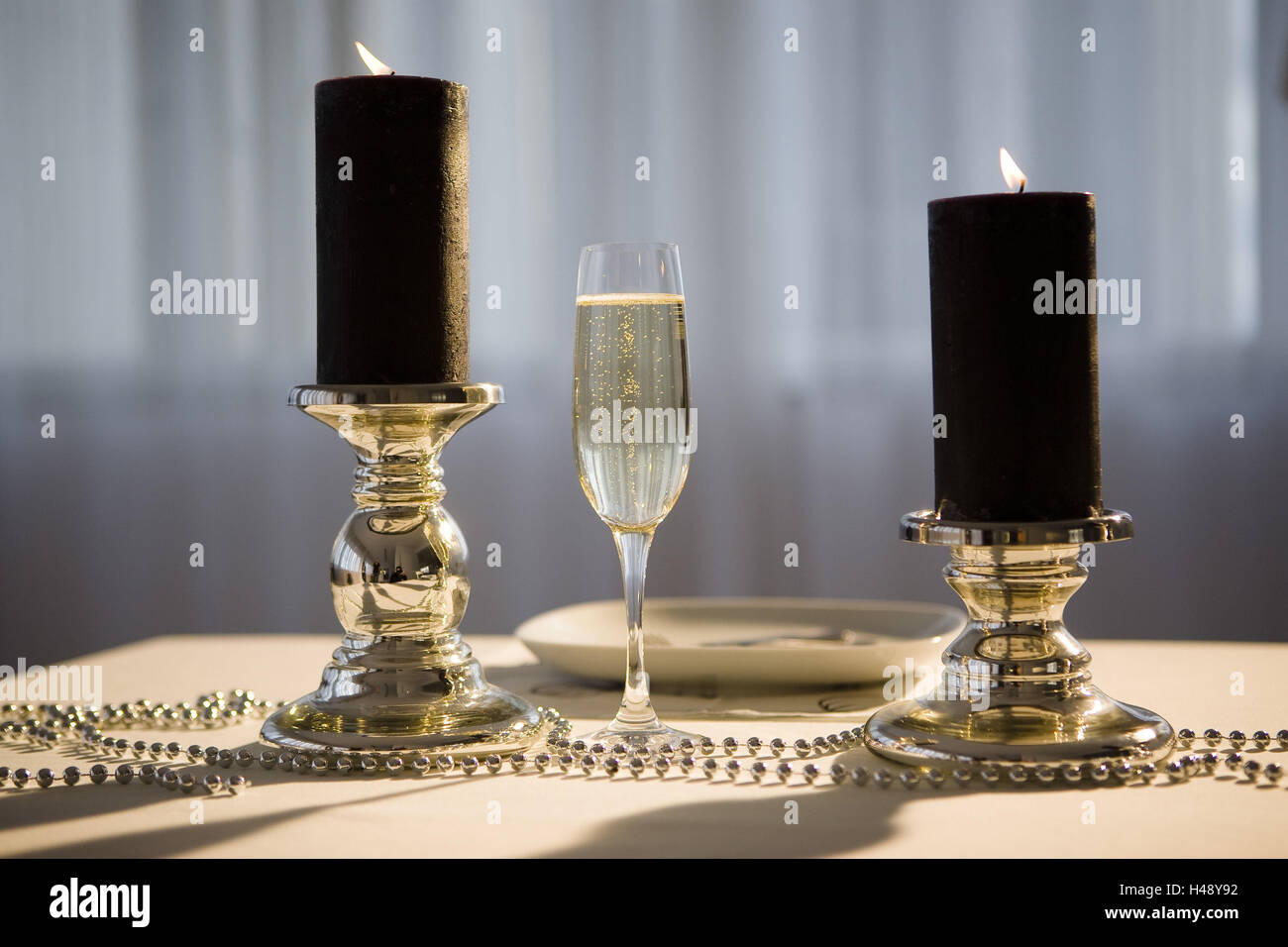 Table appointments, candle holder, champagne glass, plate, instruments ...