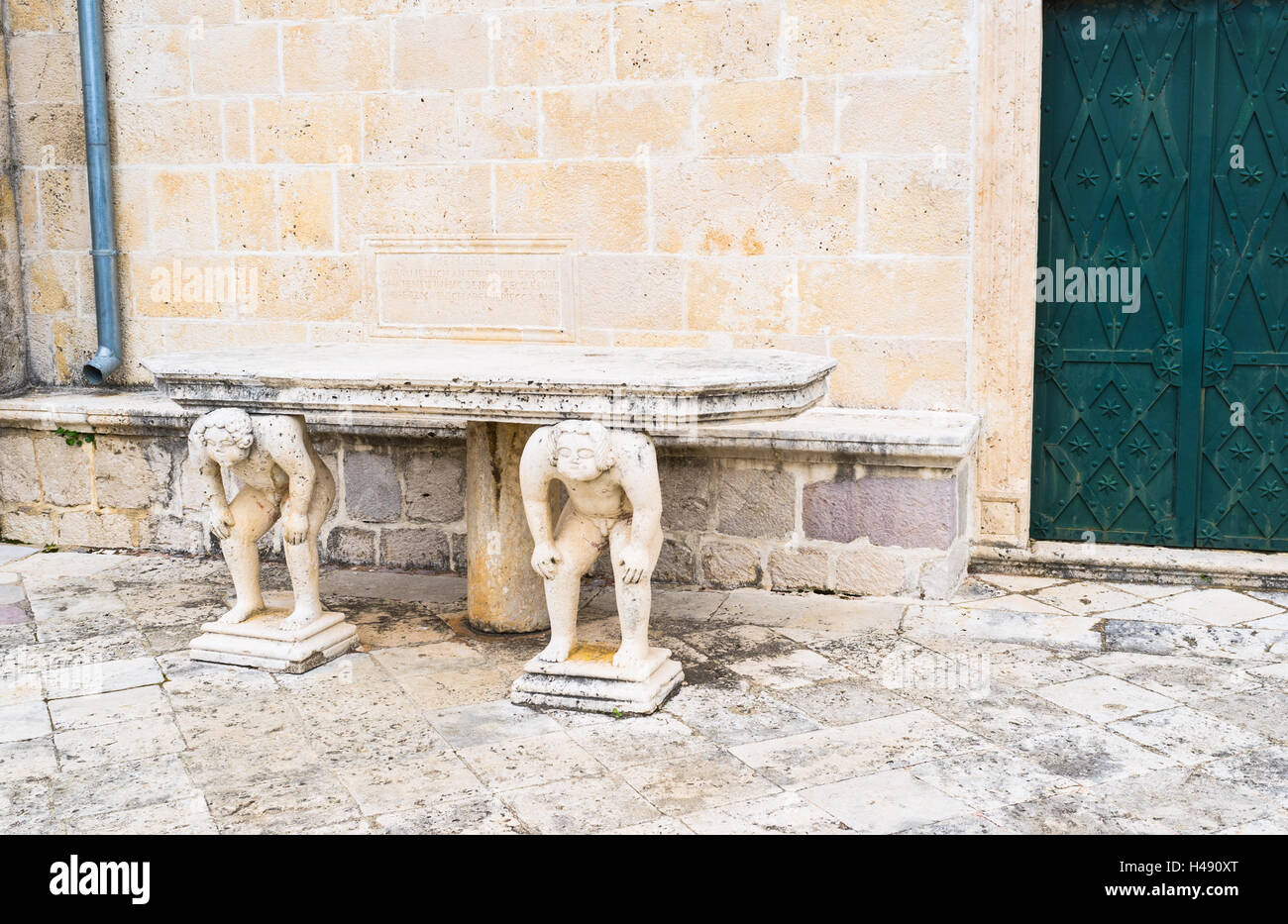 The stone table is supported by two statues of hunched men, standing ...