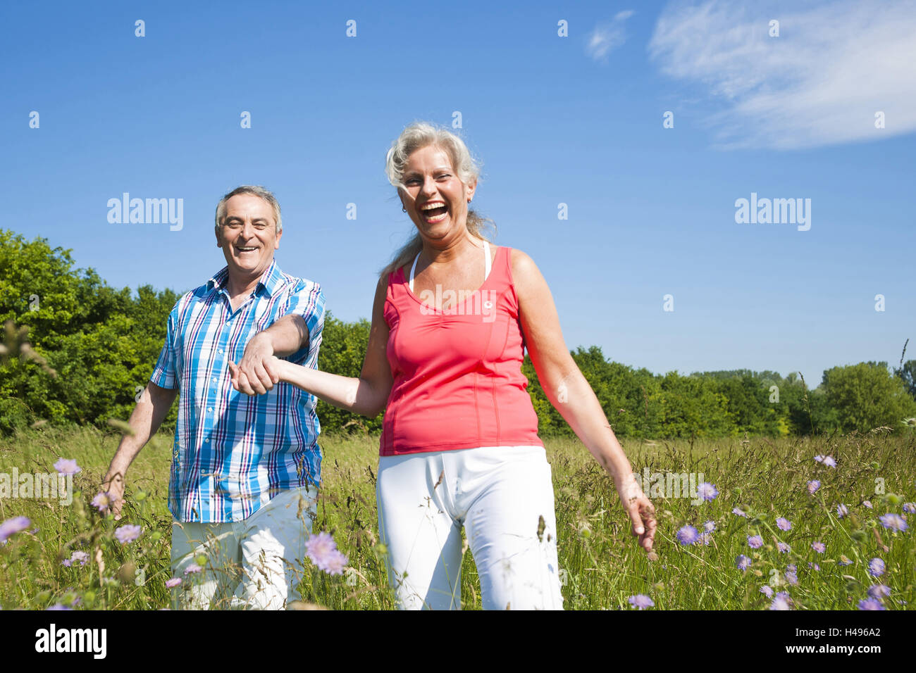 Senior couple running happily on a meadow Stock Photo - Alamy