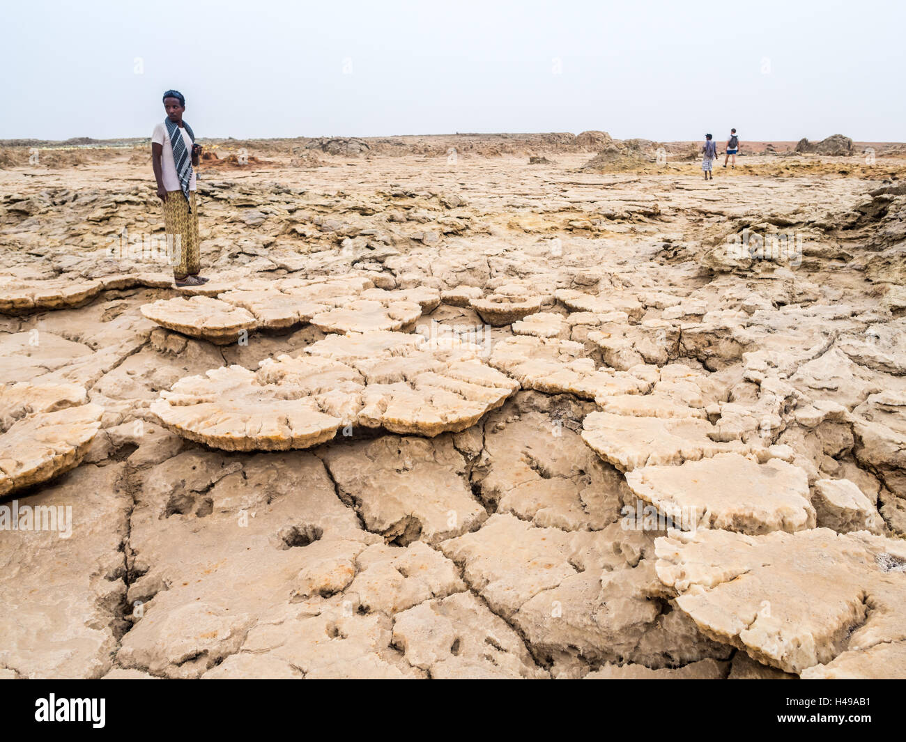 People walk across mineral soil formations around sulfur lake Dallol ...