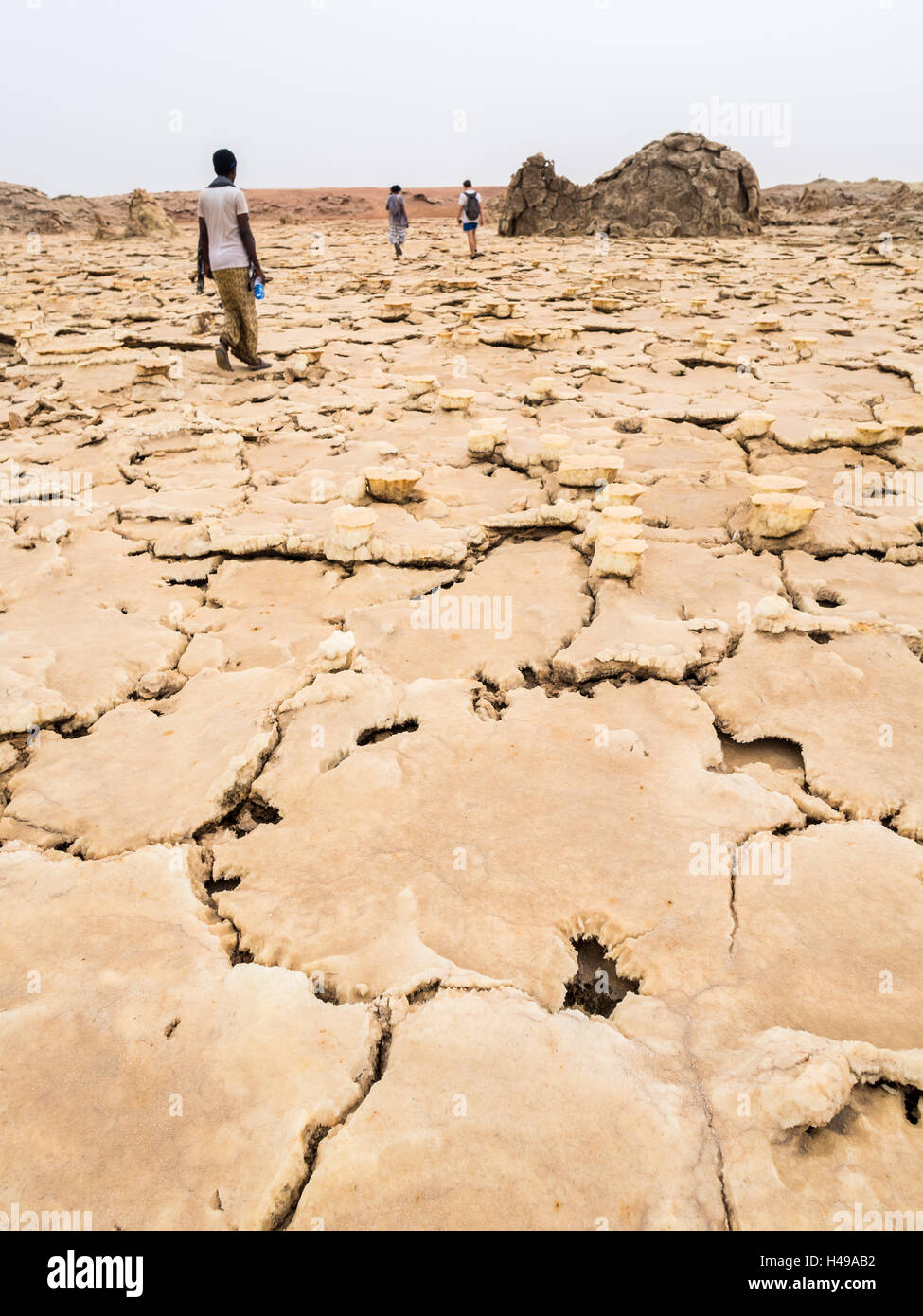 People walk across mineral soil formations around sulfur lake Dallol ...