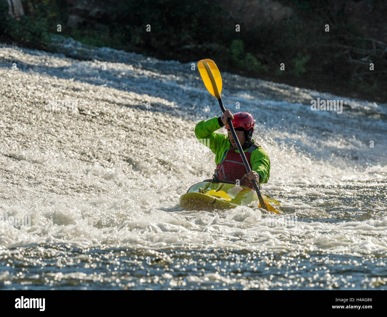 Male adult White Water Kayaking along a River Exe Weir on a bright ...