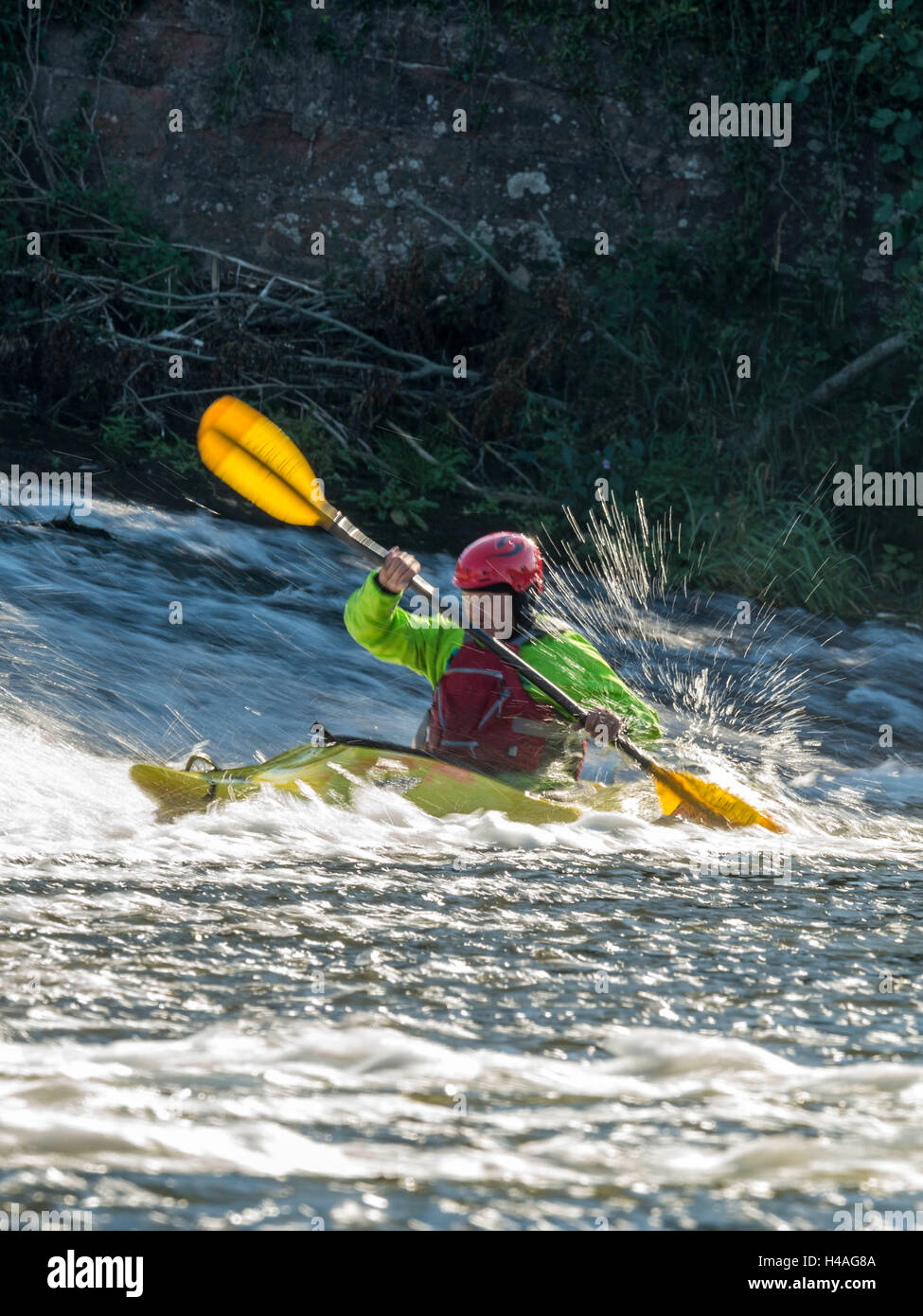 Male adult White Water Kayaking along a River Exe Weir on a bright ...