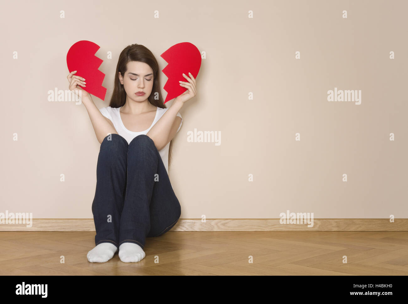 Woman holds divided heart in her hands, sits sadly on the floor Stock ...