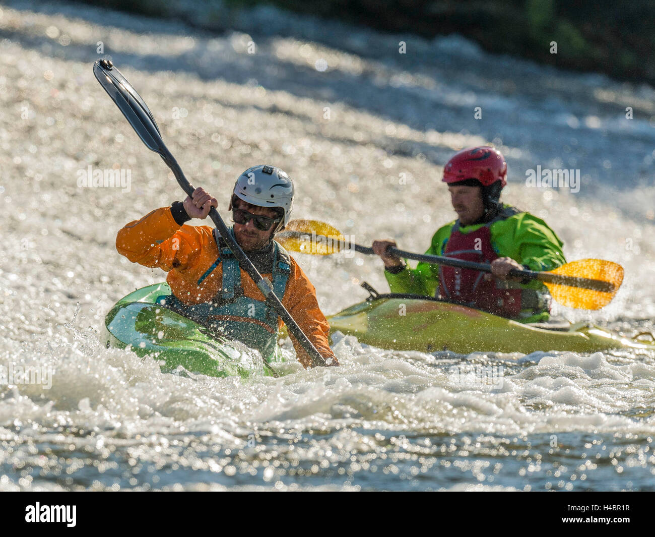 Two male adults White Water Kayaking along a River Exe Weir on a bright ...