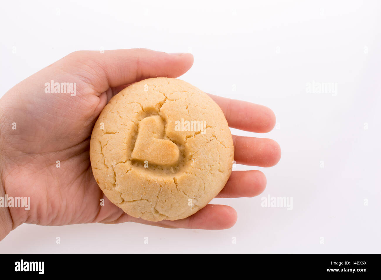 Hand holding a Light brown cookie with a pattern on a white background ...