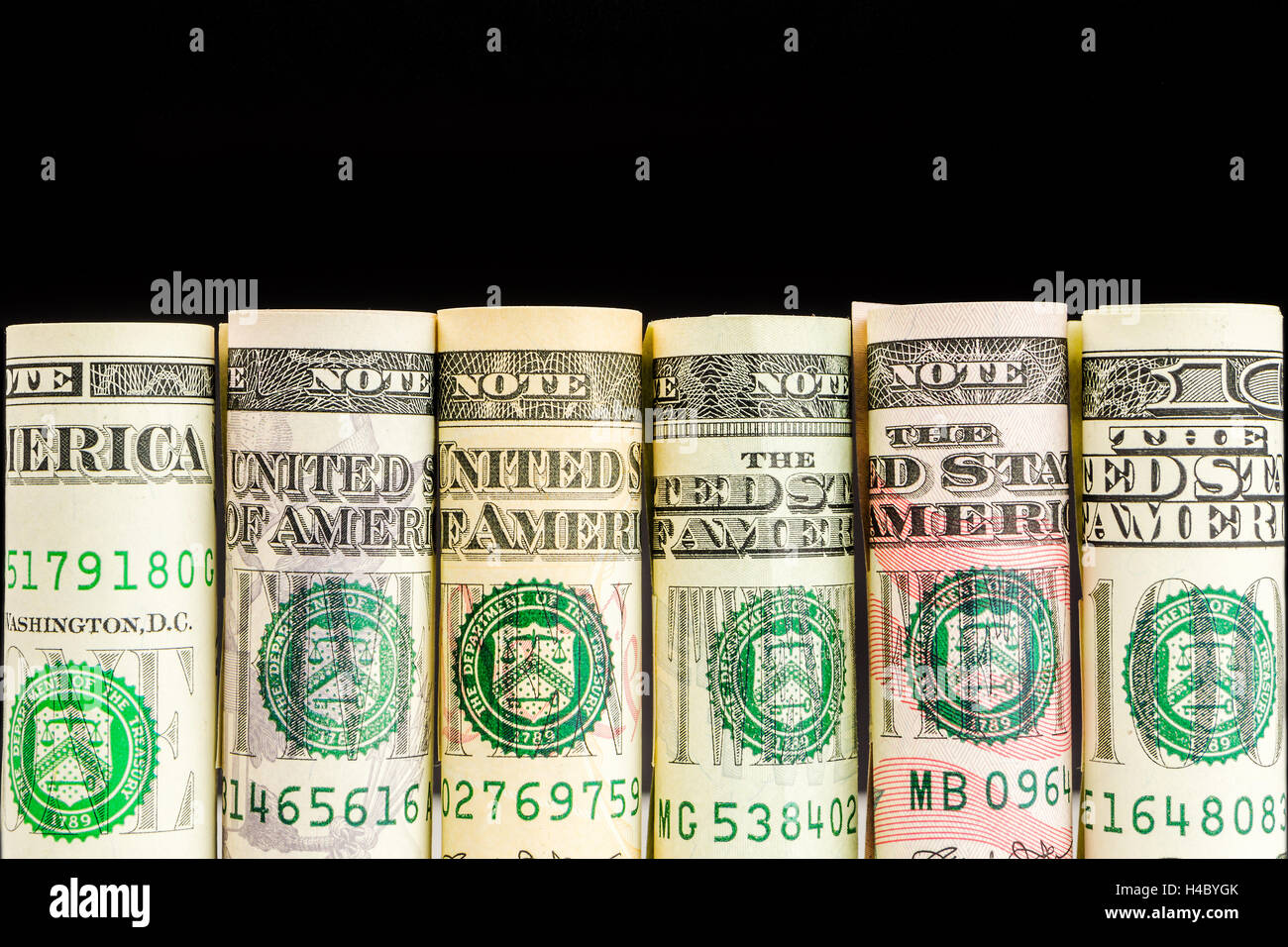 american dollar banknote rolls in all denominations in one row on black ...