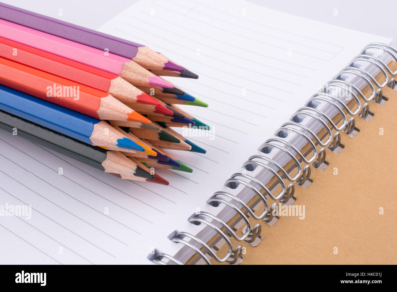 color pencils of various colors near a notebook on a white background ...