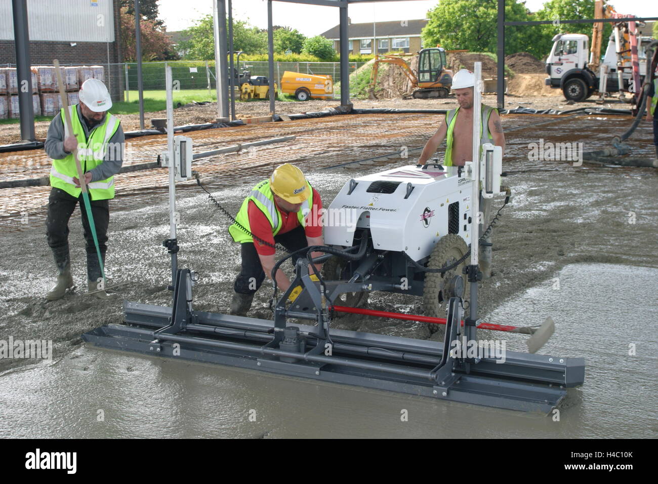 Workmen use a computer controlled, laser leveled screeding machine to ...