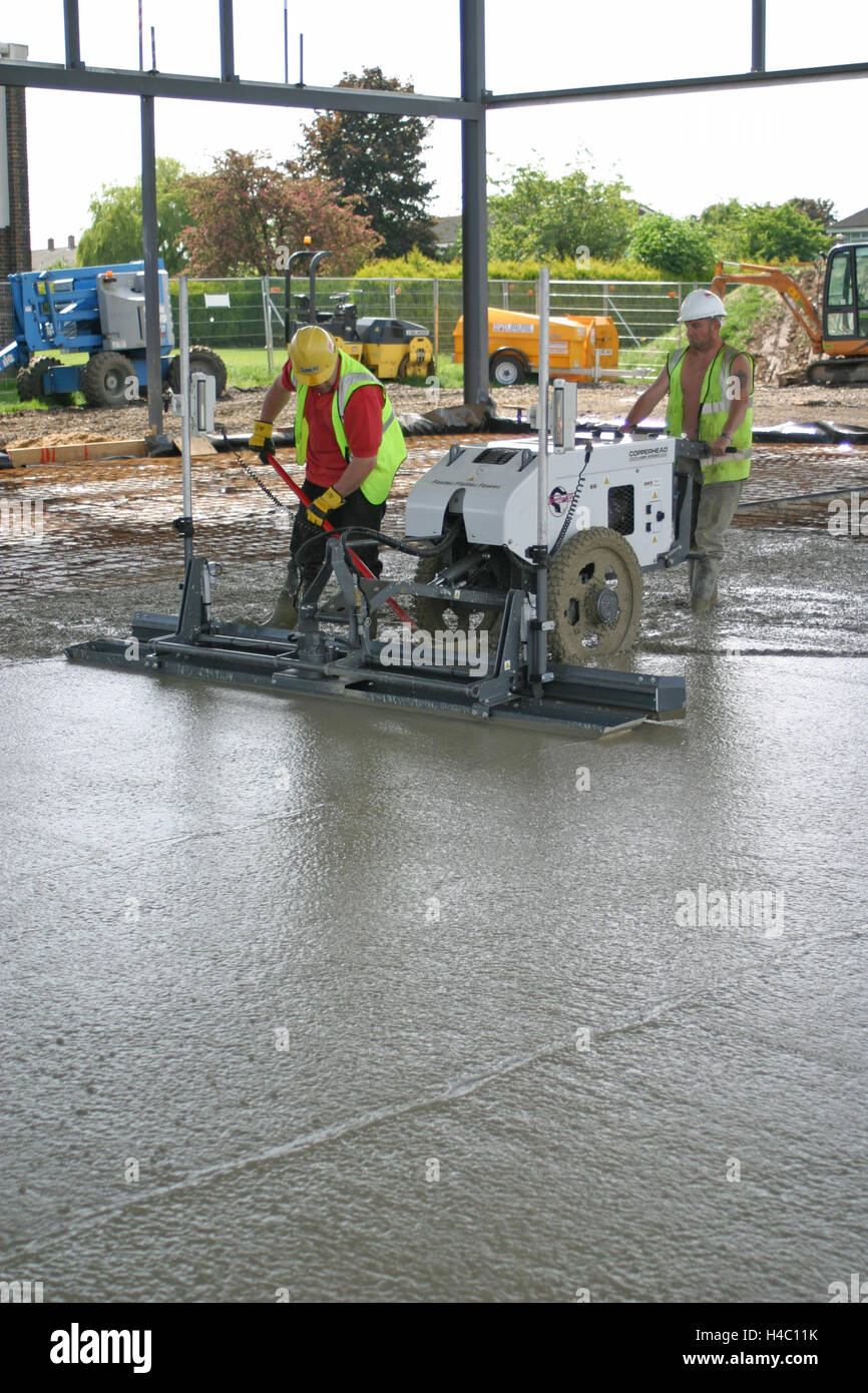 Workmen use a computer controlled, laser leveled screeding machine to ...
