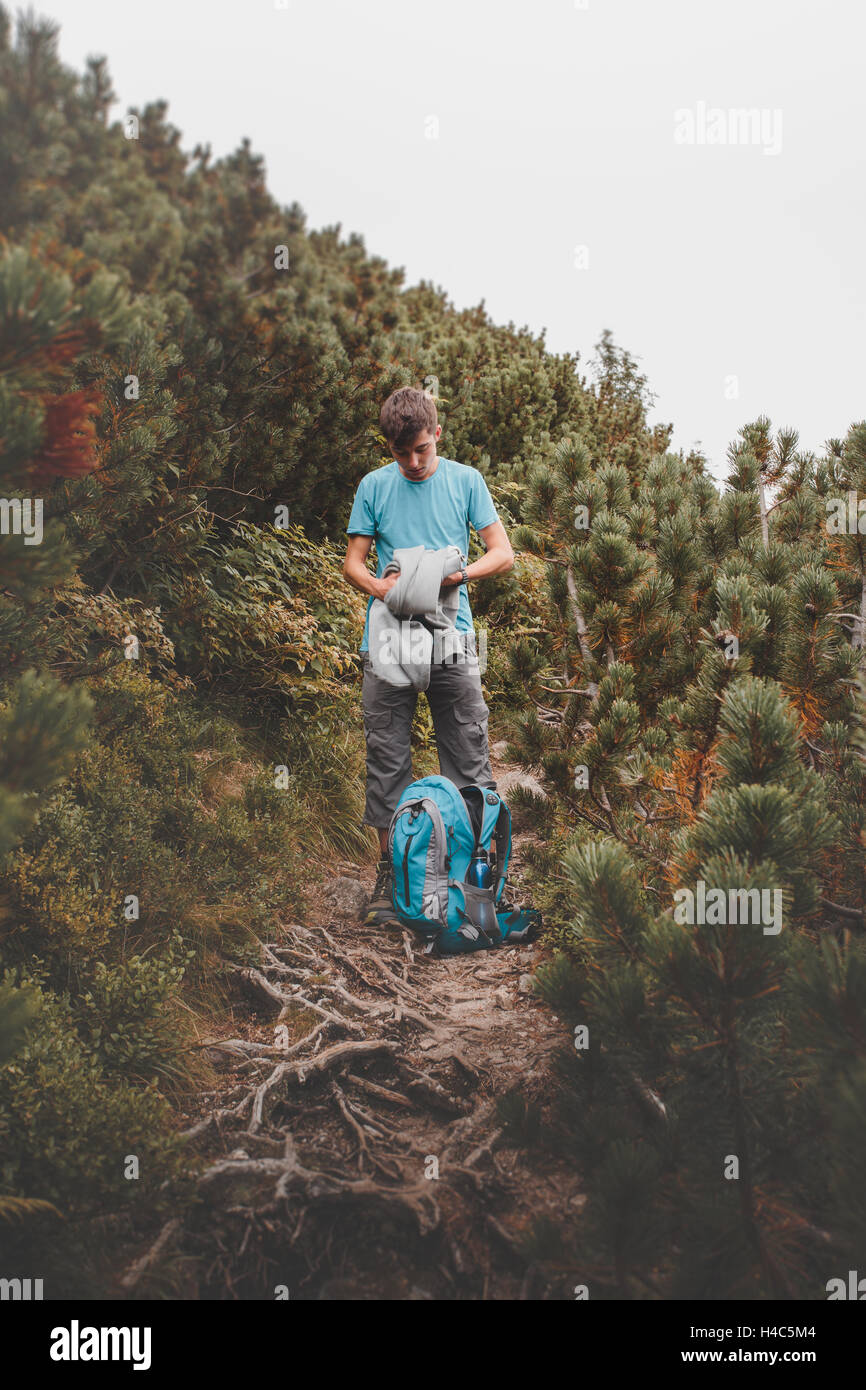 Boy packing his clothes to backpack on trail Stock Photo - Alamy