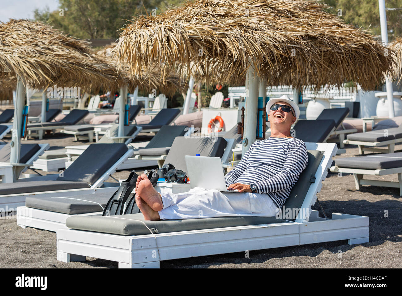 Man working at the computer lying on the beach Stock Photo - Alamy