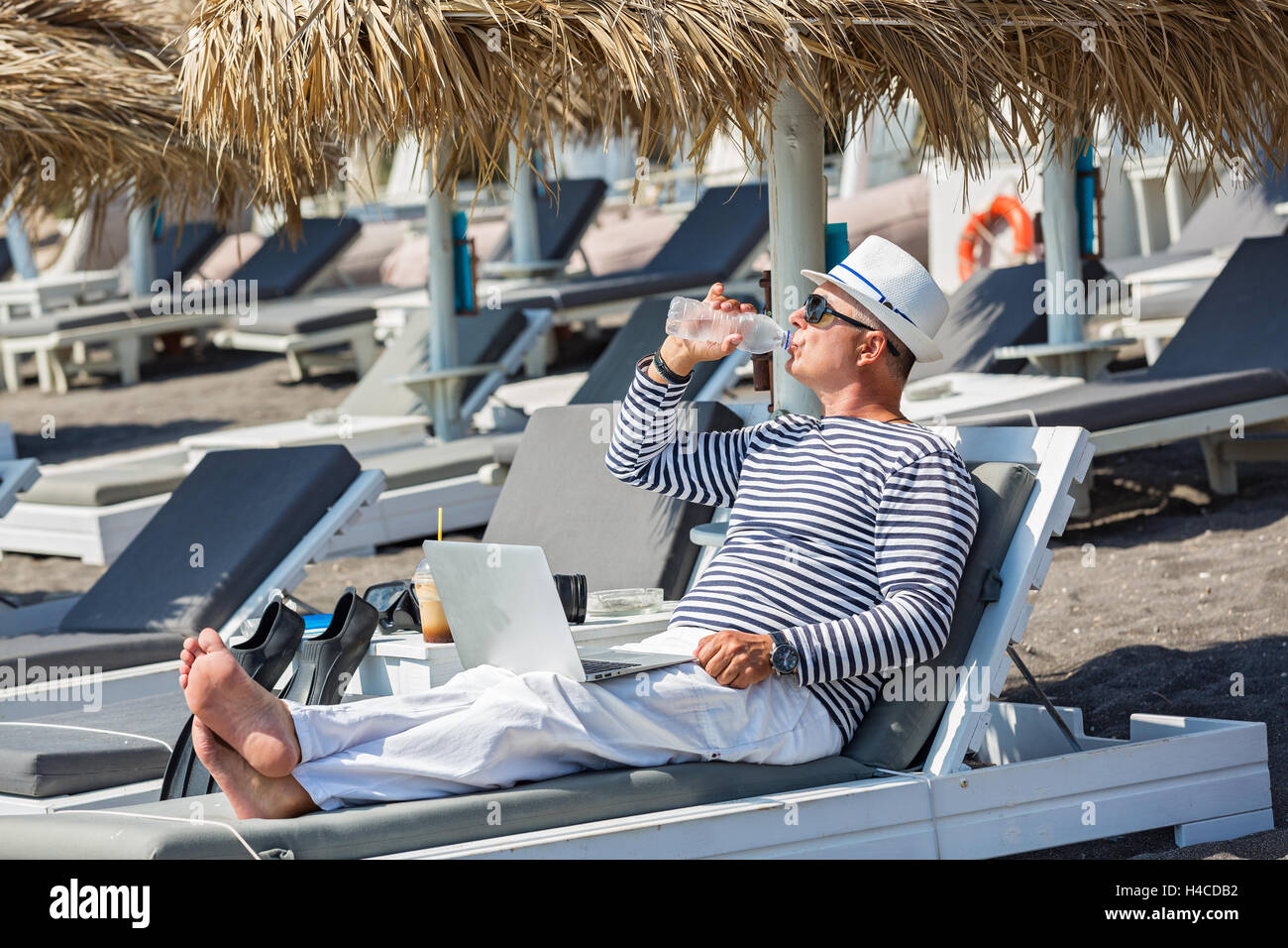 Man working at the computer lying on the beach Stock Photo - Alamy