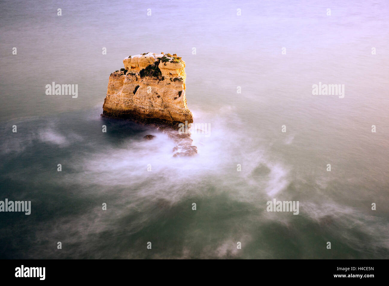 A single rock in the surf in the evening light Stock Photo - Alamy