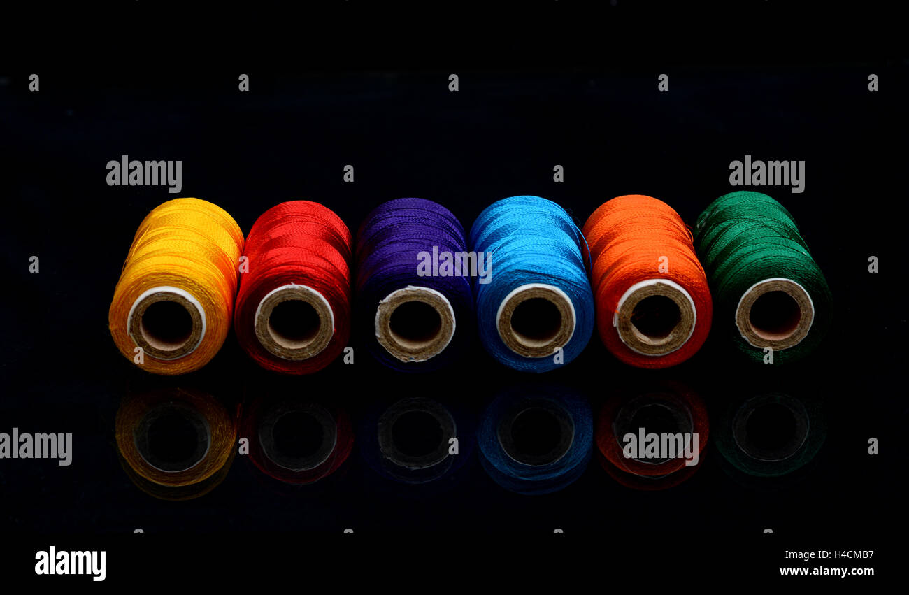 Spools of colorful silk threads on black background with reflection ...