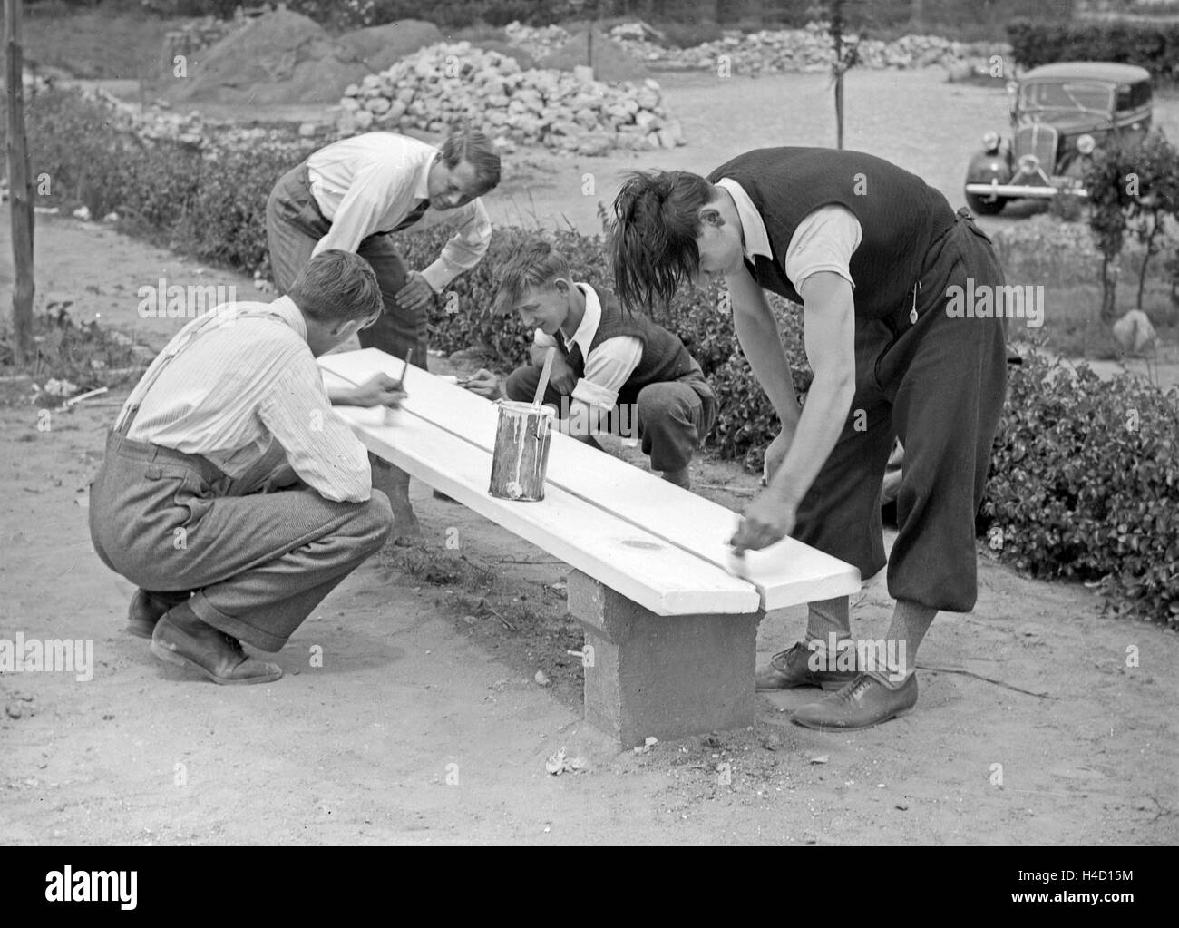 Lehrjungen streichen eine Sitzbank im Garten ihrer Berufsschule ...