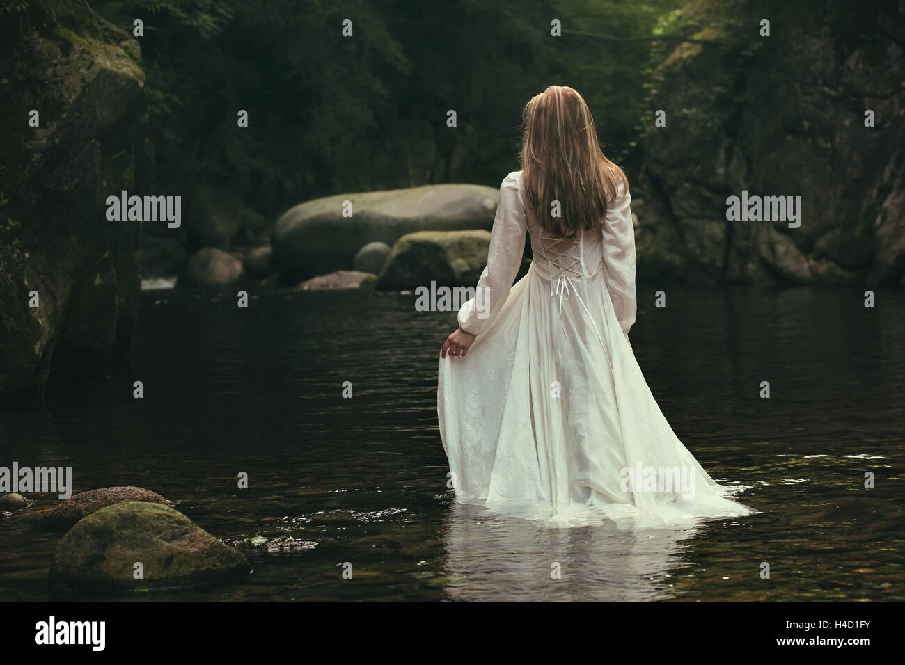 Romantic woman walks into a green stream. Ethereal and dreamy Stock ...