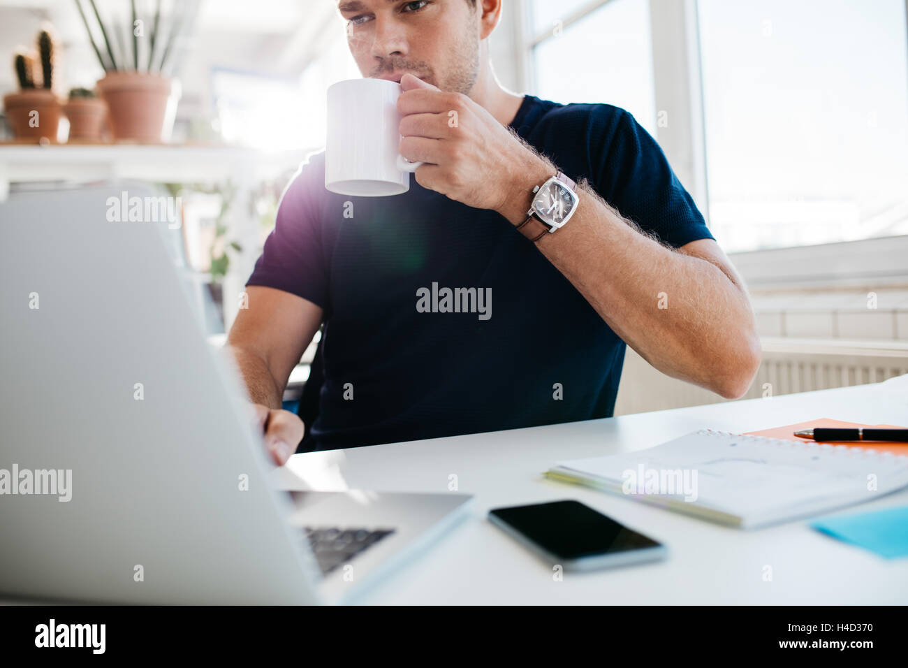 Businessman drinking coffee and working on laptop at workplace. Male ...