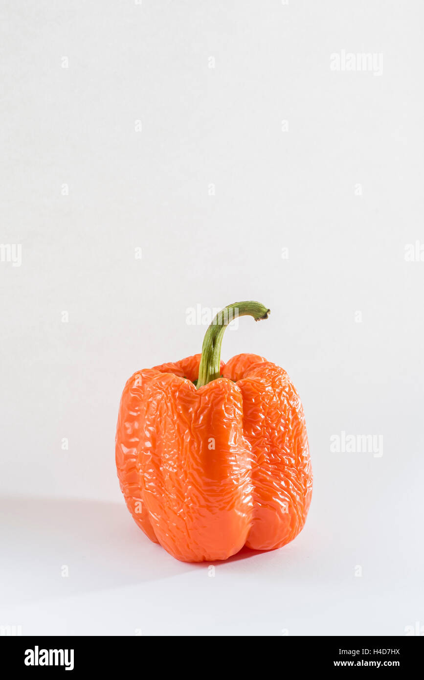 A wrinkled orange pepper with a green stalk on a white background Stock ...