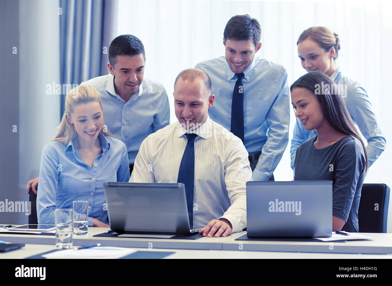 smiling businesspeople with laptops in office Stock Photo - Alamy