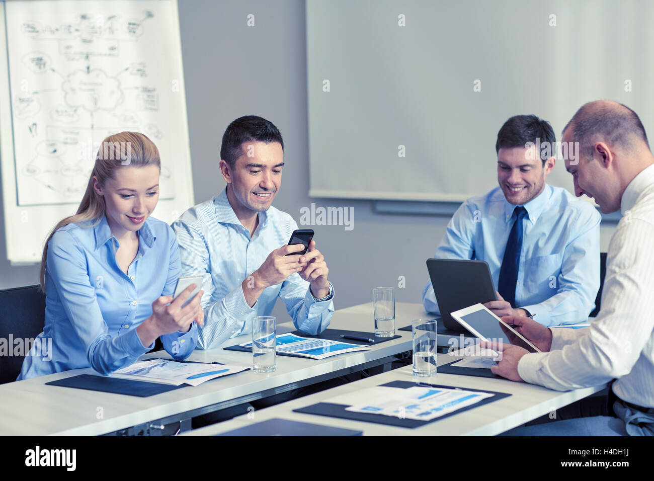 smiling business people with gadgets in office Stock Photo - Alamy