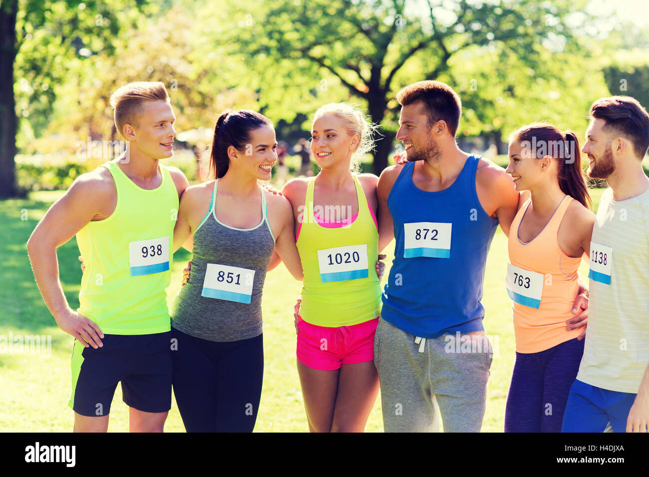 happy friends or couple with racing badge numbers Stock Photo - Alamy