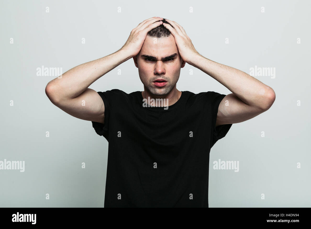Worrying man posing at studio with arm on head Stock Photo - Alamy