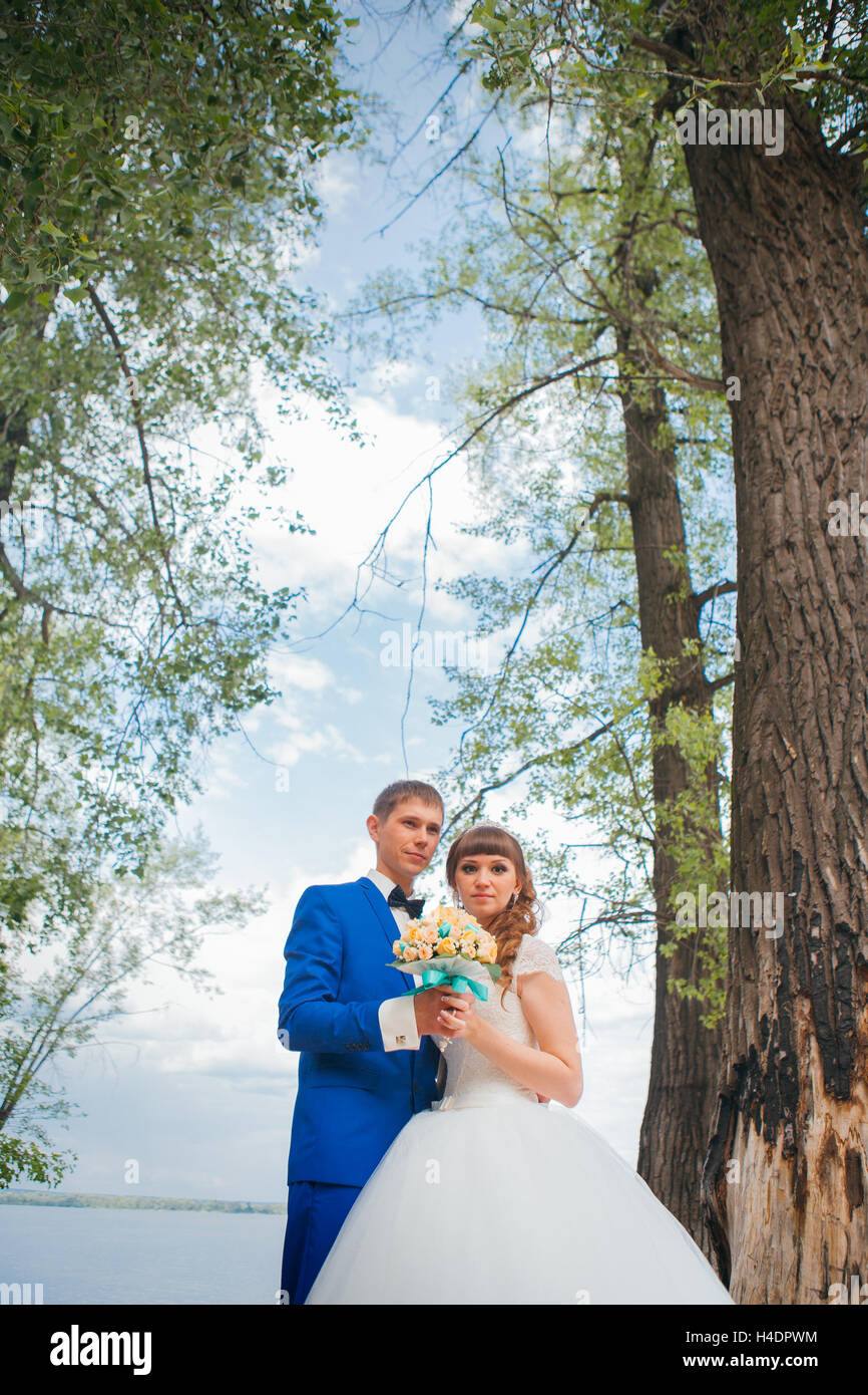 bride and groom standing and hugging on the background of trees Stock ...