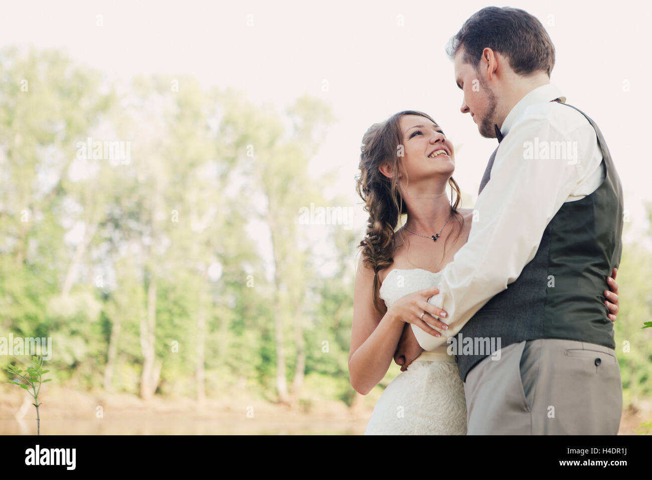 bride and groom standing arm in arm against the background grass and ...