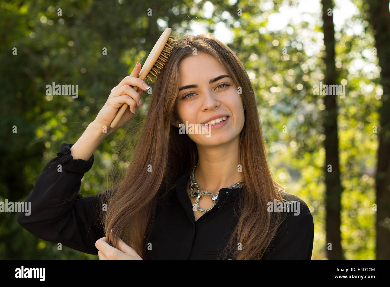 Woman combing her hair in the park Stock Photo - Alamy