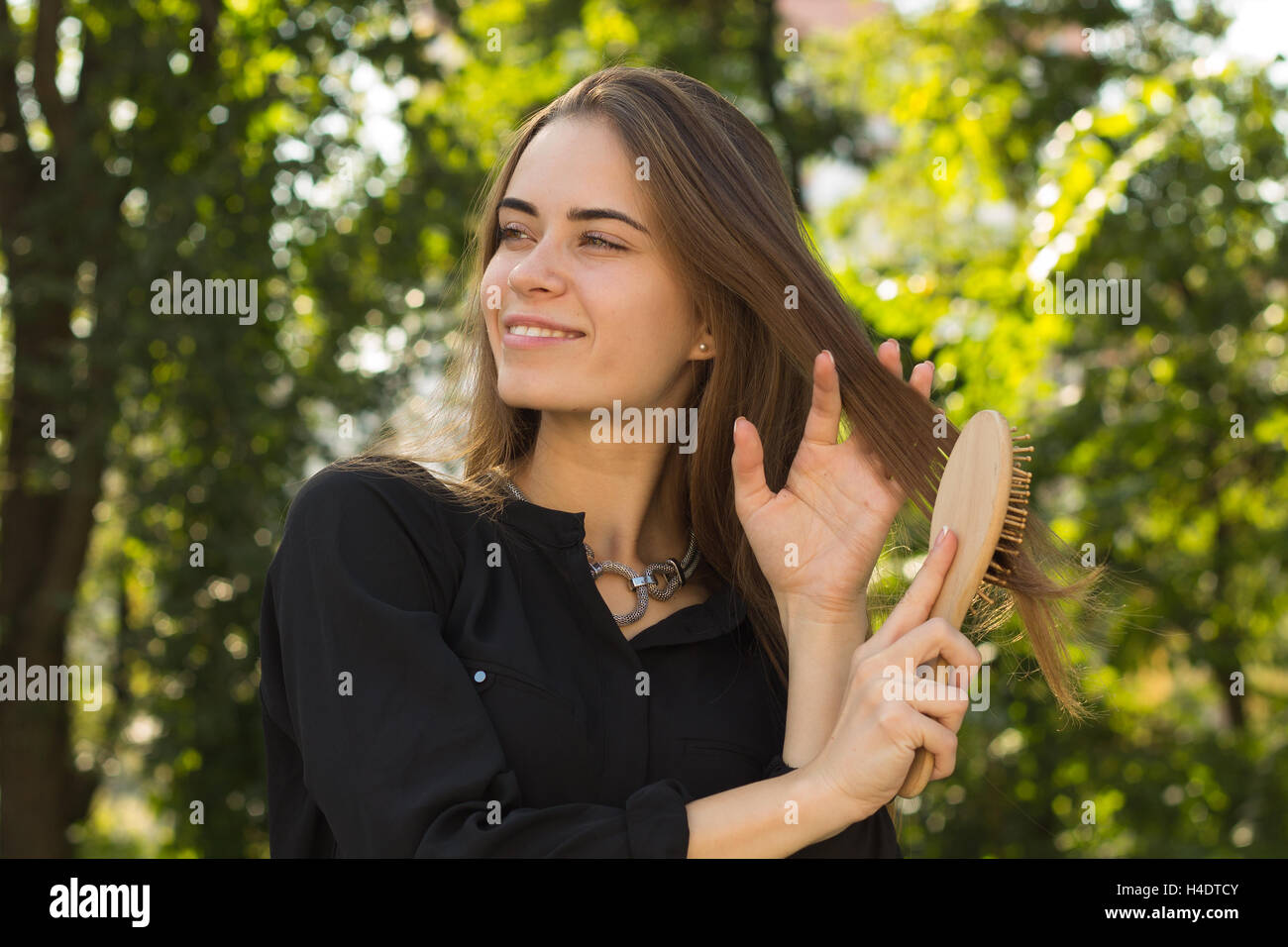 Woman combing her hair in the park Stock Photo - Alamy