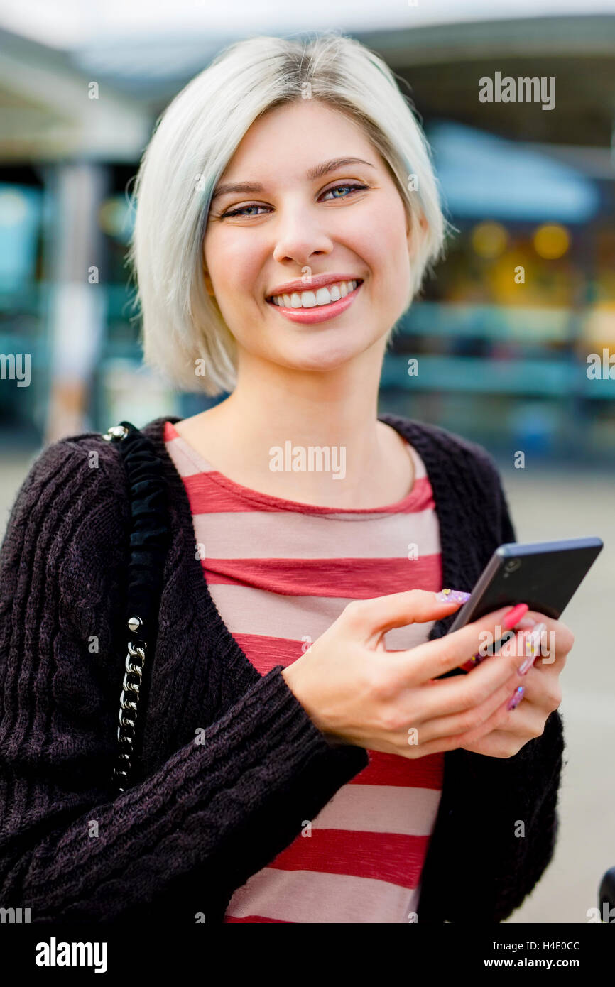 Woman Smiling While Using Smart Phone Outside Train Station Stock Photo ...