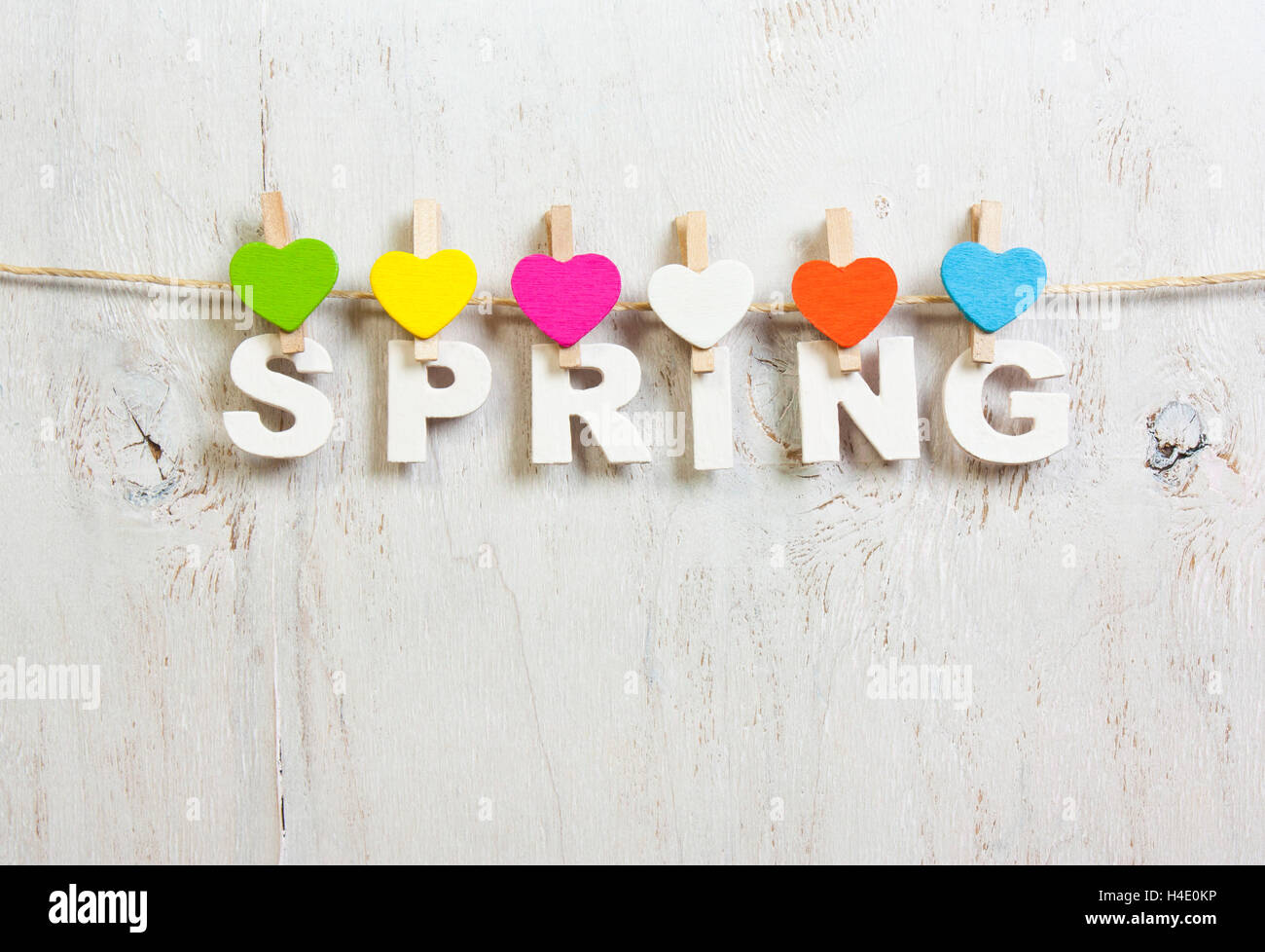 word spring with white letters with colored hearts clothespins on a ...