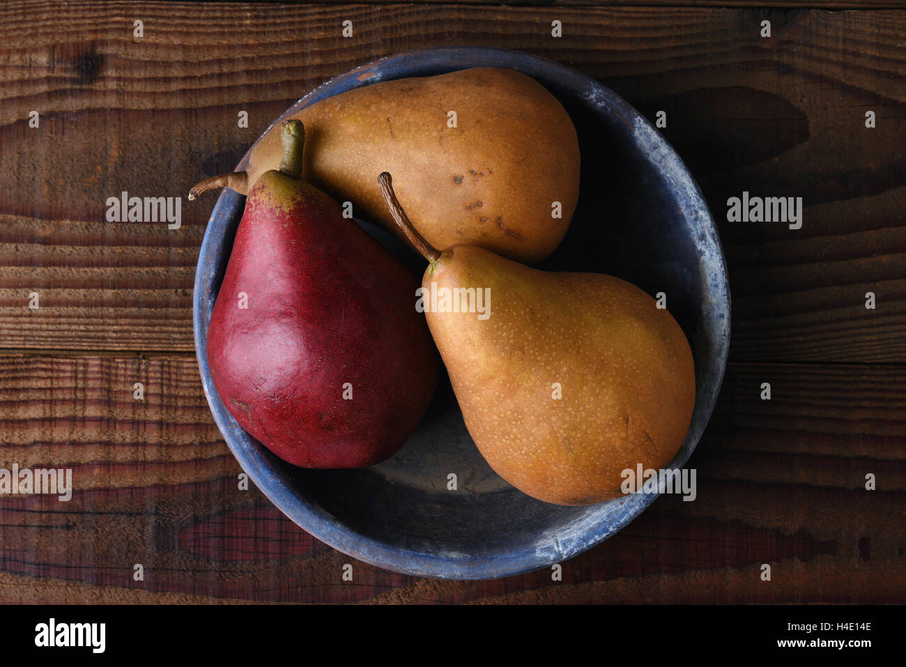 Top view of a group of Red and Bosc pears in a blue plate on a rustic ...