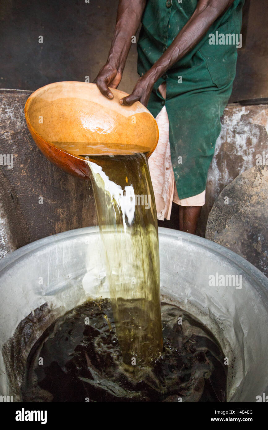 An employee processes shea butter into oil at a fair trade production ...
