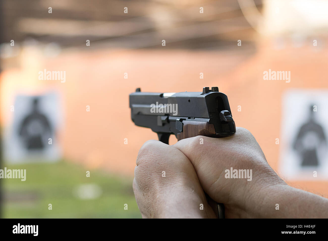 Shooting with a pistol. Man aiming pistol in shooting range Stock Photo ...