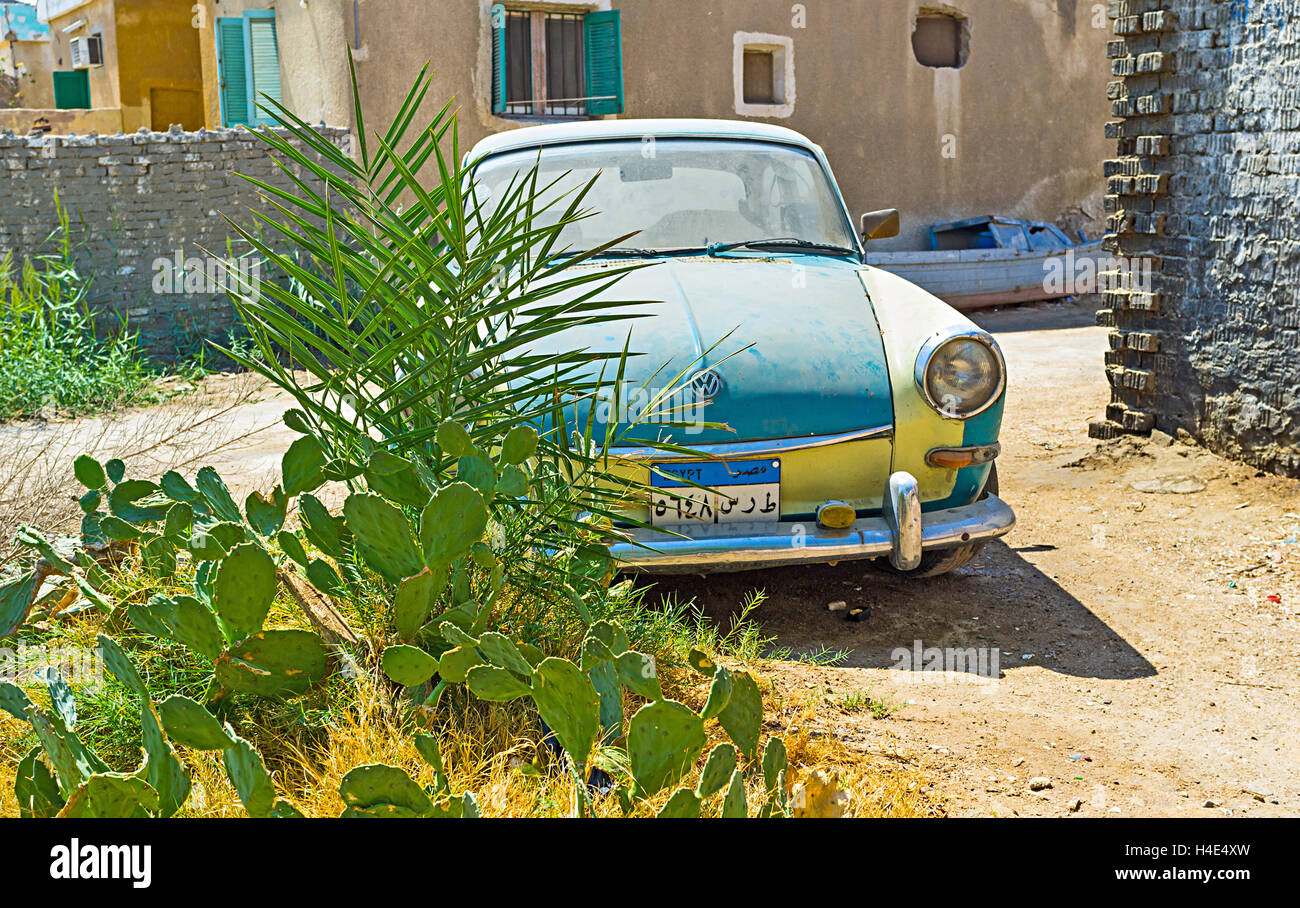 The old car is parked next to the house in poor residential ...