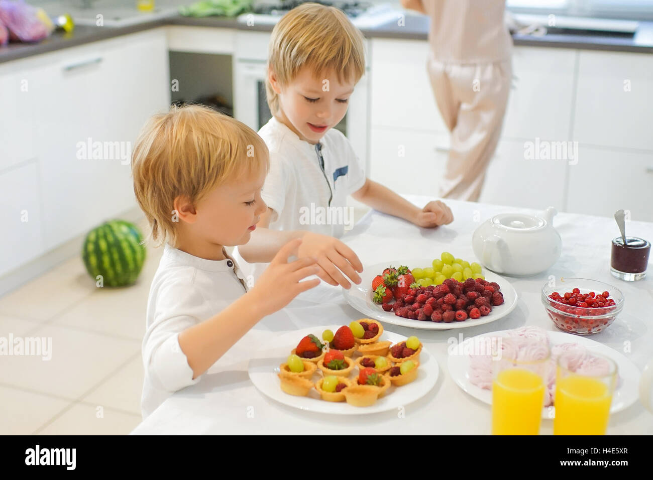 Two boys preparing breakfast in white kitchen Stock Photo - Alamy