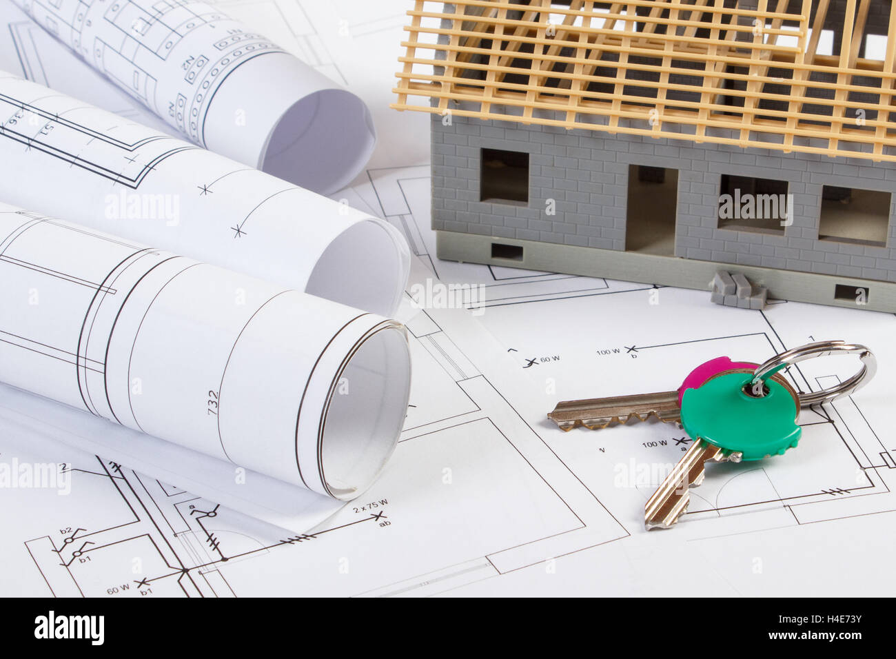 Home keys, small house under construction and rolls of diagrams on ...