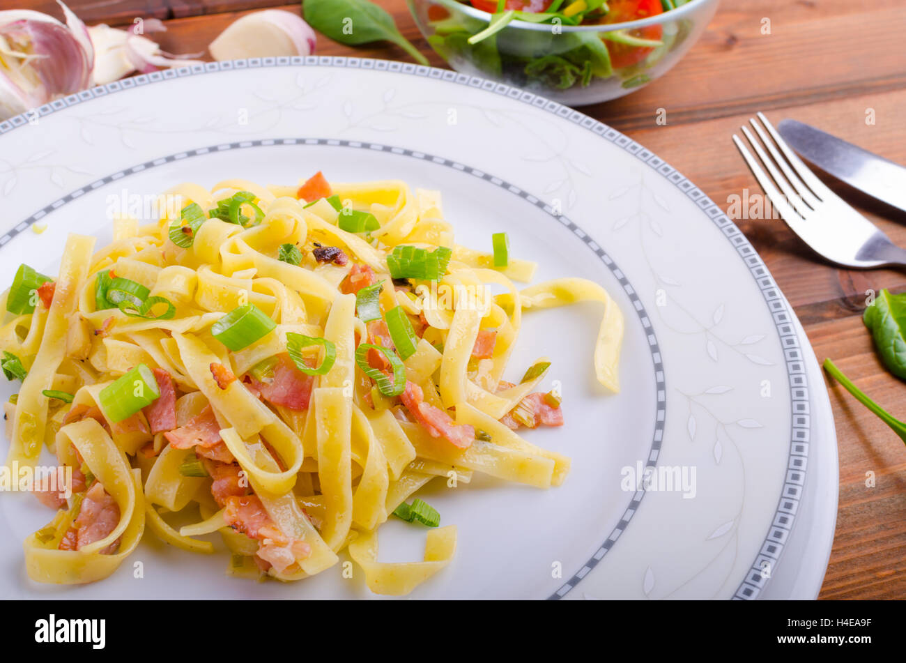 Italian pasta with spring onion, garlic and bacon with salad Stock ...
