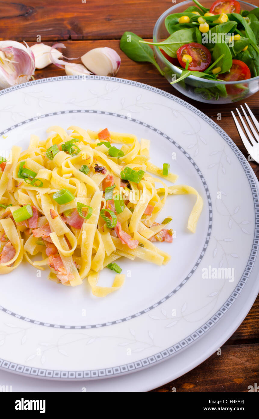 Italian pasta with spring onion, garlic and bacon with salad Stock ...