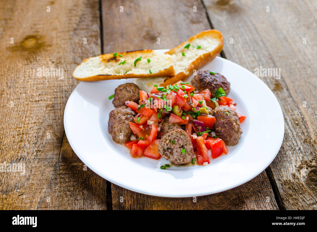 Meatballs with spicy tomato salsa, baked baguette and basil on top ...